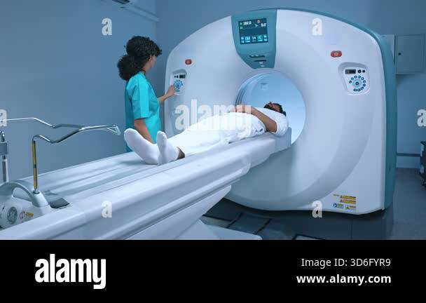 Neurosurgeon presses settings button of MRI scanner, during positron ...