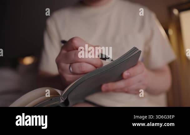 Mans hands holding a pen writing notes in a small pocket diary ...