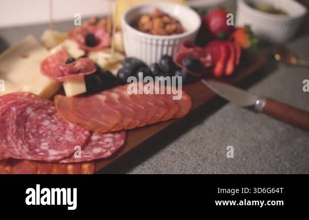 Charcuterie board presenting sliced meats, cheeses, fruits, and nuts ...