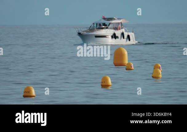 A luxury motor yacht cruises gently across calm blue waters, passing ...