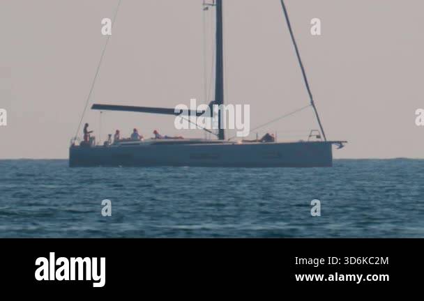 A luxury sailboat with several people onboard cruising peacefully ...