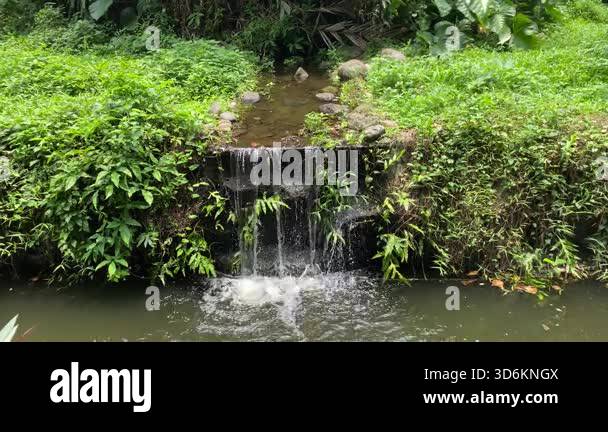 Waterfall from the small water conduit to the wider river under ...