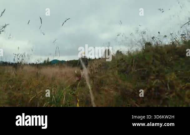 A low-angle handheld tracking shot follows an unrecognizable woman seen ...