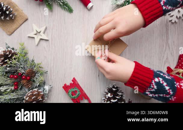 Horizontal slow-motion shot of a girls hands tying rustic twine on a holiday gift box during ...