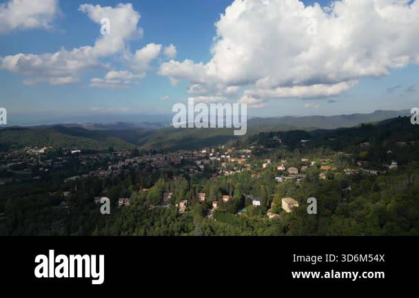 Aerial footage showing a small town nestled in a green, wooded valley ...