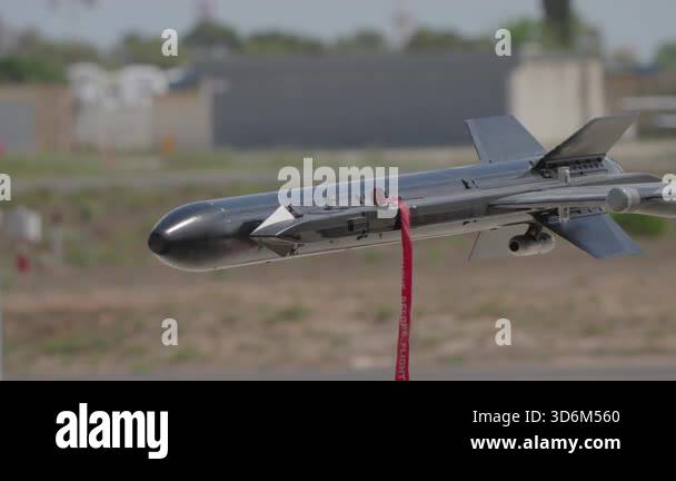 Close up of a black missile mounted under an aircraft wing with a red ...