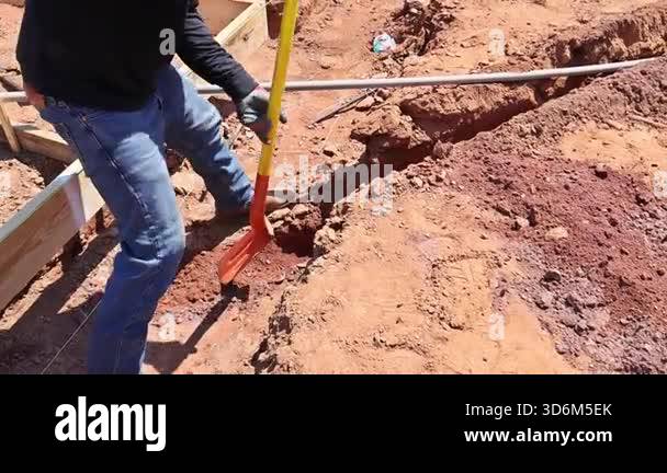 Construction worker is using digging tool to excavate soil at building ...