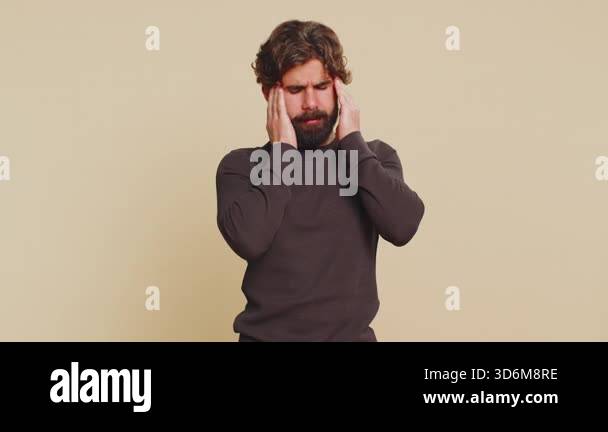 Lebanese bearded man in long sleeves rubbing temples to cure headache ...