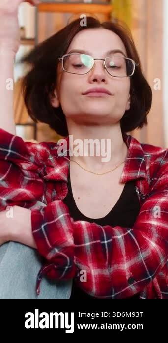 Young woman sits on home sofa with sad face, thinking deeply about ...