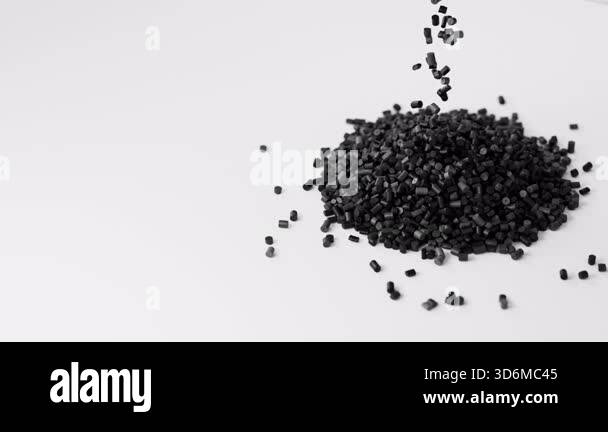 Black plastic polypropylene granules pouring from cup on a pile of ...