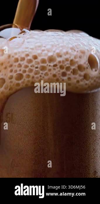 Foam rising from pouring dark beer into glass mug closeup. Concept of ...