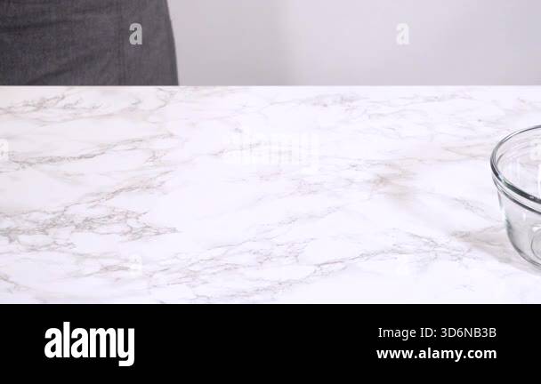 A person arranges a set of gold-colored measuring cups on a white ...