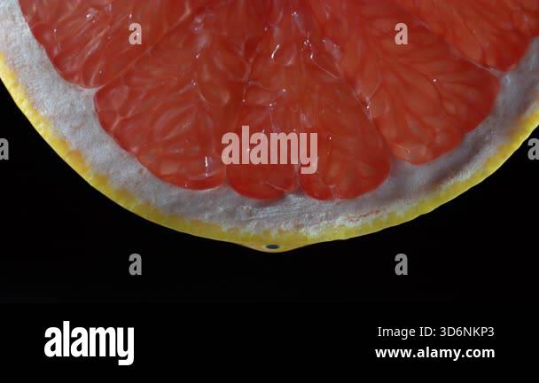 Juicy red grapefruit slice with drop on black background . Texture ...