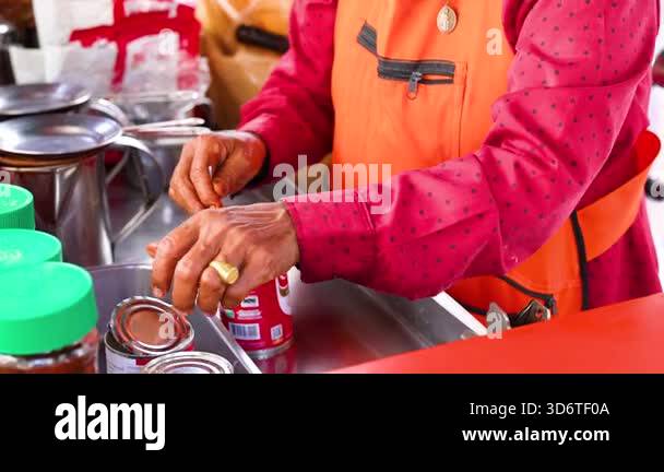 A vendor in Phuket prepares tea using condensed milk and spices ...