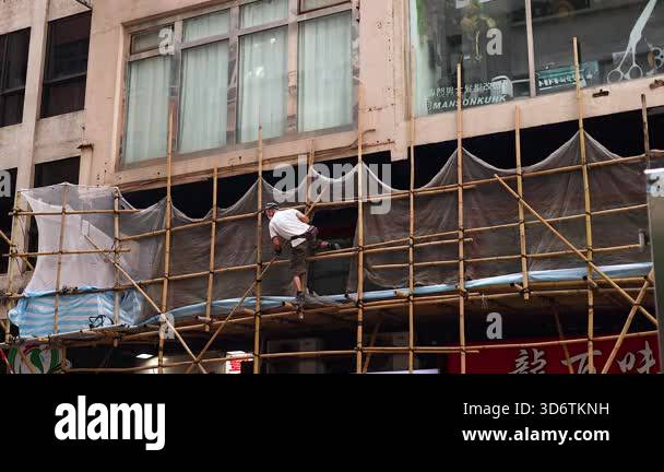 Worker climbs bamboo scaffolding on building facade Stock Video Footage ...
