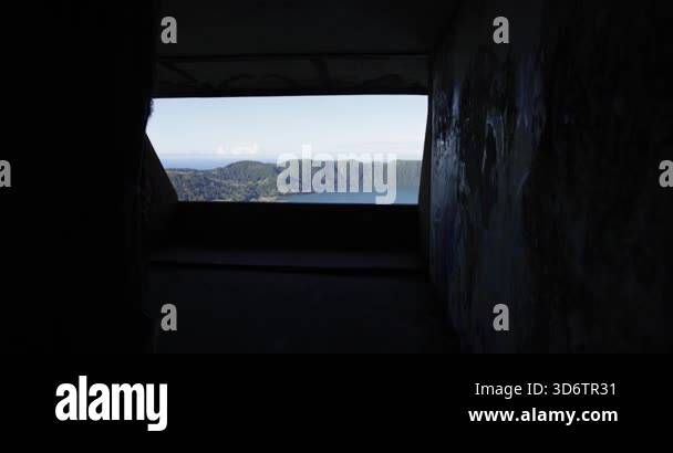 A window in a building revealing a view of a lake and mountains at Sete ...