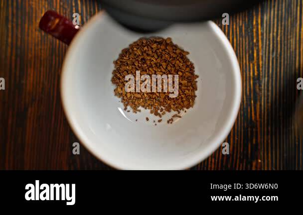 Pouring hot water into cup of instant coffee. Closeup top view showing ...