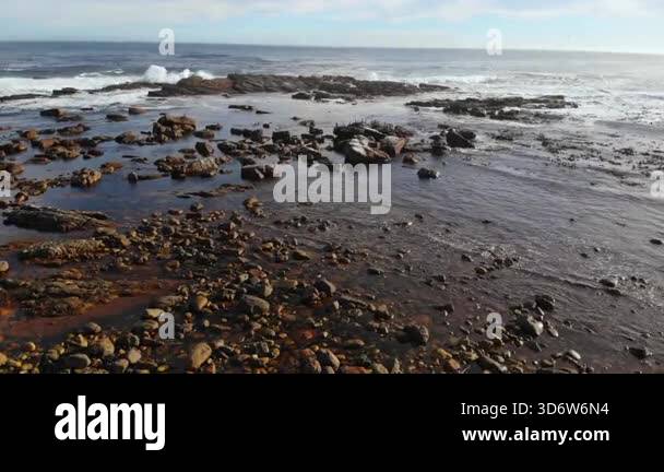 Incoming tide slowly floods a rocky coast with gentle waves breaking on ...