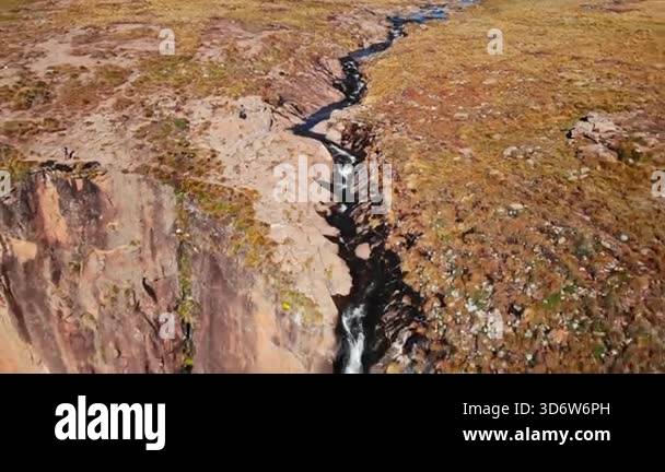 Majestic waterfall cascading down a sheer rock face in a dramatic, arid ...