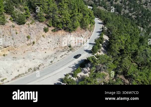 Adventure drive: drone footage of a single car traversing a remote mountain road through the ...