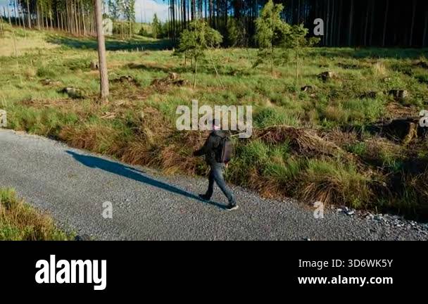 Person walking beside forest clearing on gravel path during sunny ...