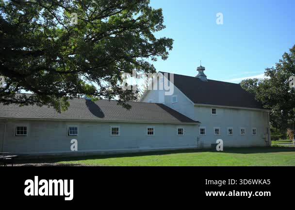shot of a historic white wooden barn on a sunny day, surrounded by a ...