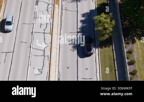 Top-down aerial drone shot of a Tesla car driving on suburban road. EV ...