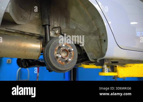 Mechanic repairs wheel hub and disk brake on the car, car is lifted ...