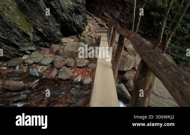 Narrow wooden footbridge with rustic handrails stretches along a rocky ...