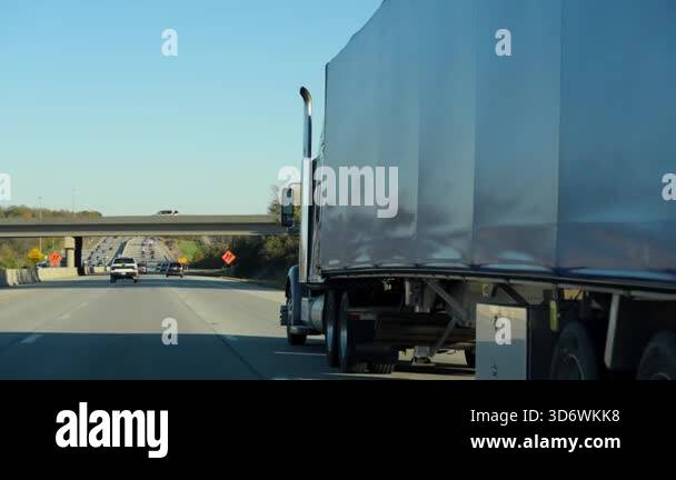 Semi truck hauls cargo along a busy interstate highway on a clear day ...