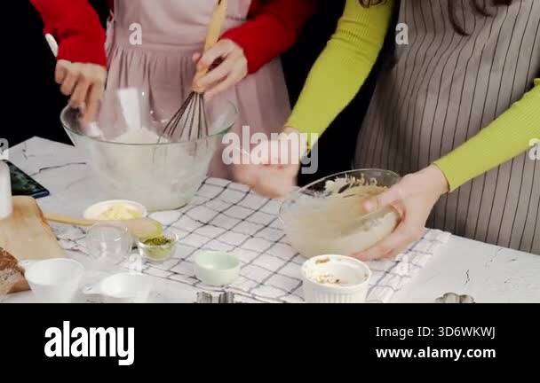 Two people mixing cookie dough together in glass bowls with flour ...