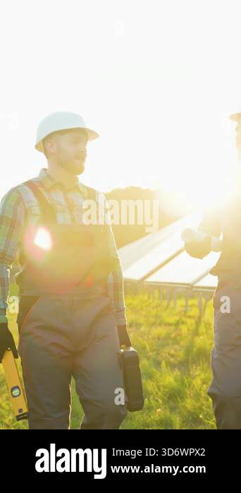Two male engineers in protective helmets and work uniforms walking and ...