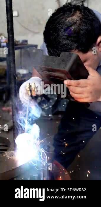A professional welder working on a metal object, holding a protective ...