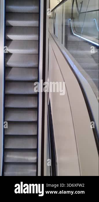 Empty metal steps of an escalator moving upwards inside a modern ...