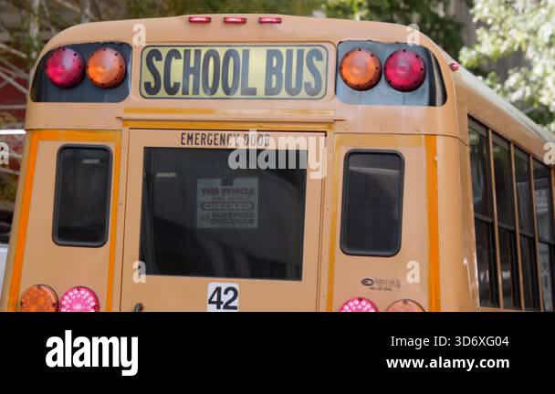 Rear view of classic yellow school bus with its emergency door, signal ...