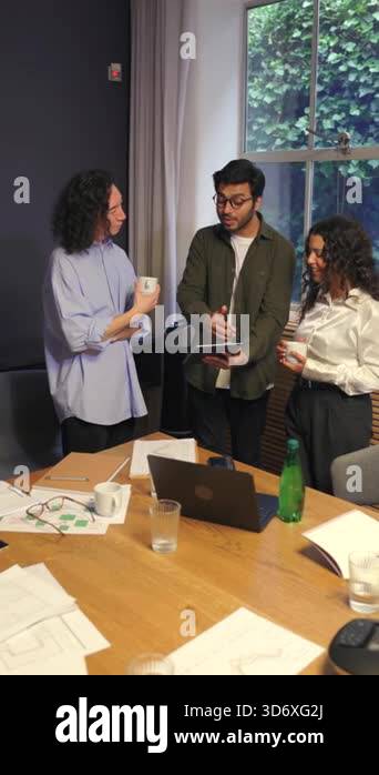 Diverse business people standing near a table with laptop and papers ...