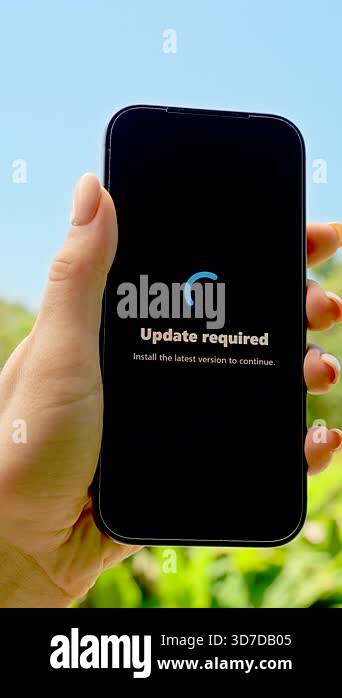 Vertical video. Smartphone in Hand Displaying Update Required Screen ...