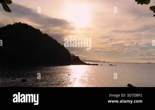 Sun Setting Behind Island Silhouette Reflecting on Calm Sea Surface ...