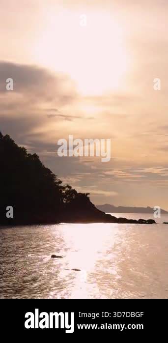 Sun Setting Behind Island Silhouette Reflecting on Calm Sea Surface ...