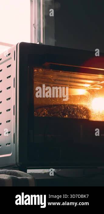 Vertical video. Electric Oven Baking Dish with Steam Rising in Dimly ...