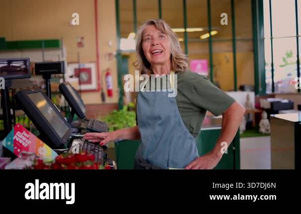 Portrait of a friendly senior female cashier working at a grocery store ...