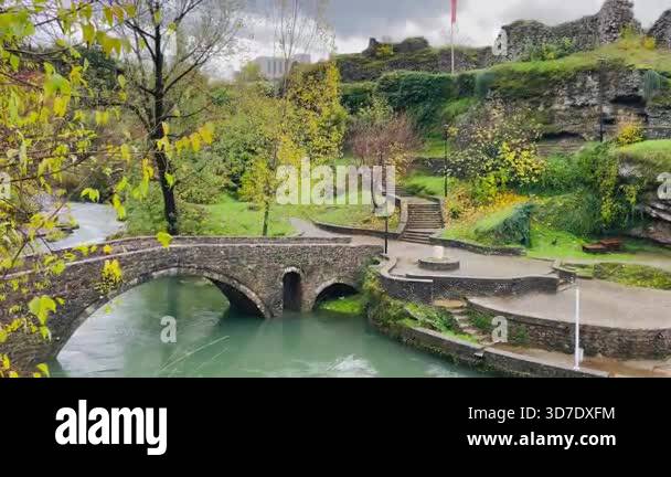 Stone bridge over emerald river, secluded riverside park with autumn ...
