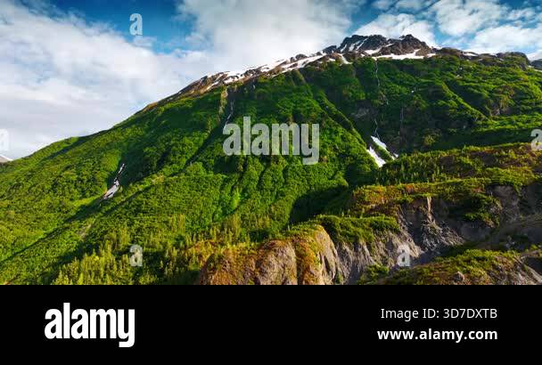 Green mountain slopes with summer snow. Bright green Alaskan slopes are ...