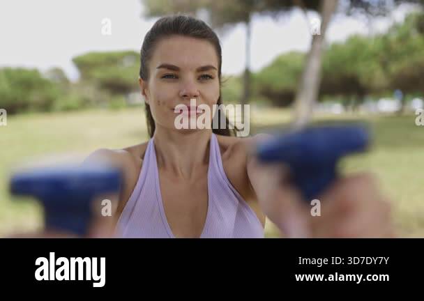 Young athletic woman performing lateral raises with dumbbells during an ...