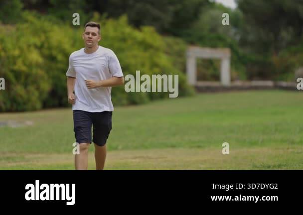Athletic man jogging towards the camera during an outdoor workout in a ...