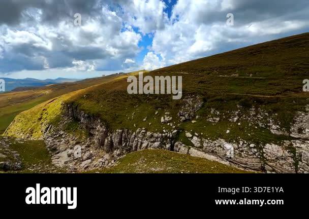 Vertical rock face of a mountain cliff. The jagged stone texture shows ...