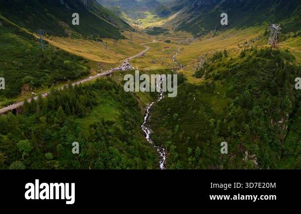 Mountain valley with long waterfall and road. A tall cascading ...