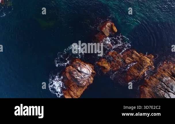 Spectacular deep blue waterscape splashes by the boulders sticking out ...