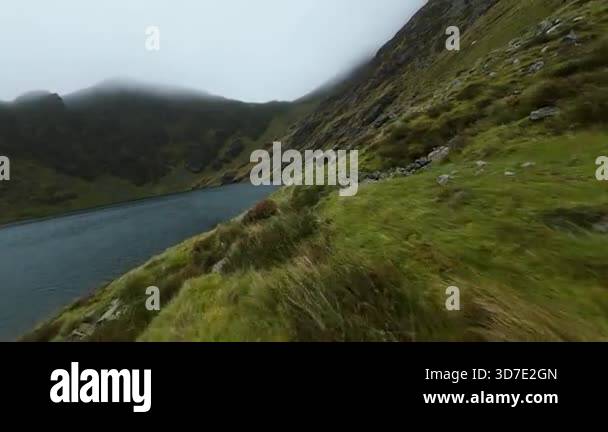 An epic aerial view of Llyn Cau, a mountain lake cradled by a moraine ...
