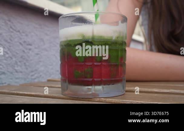 A close-up shot of an iced matcha drink with strawberry syrup in a ...